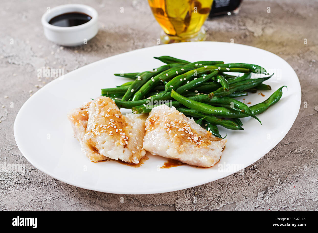 Fish fillet served with soy sauce and green beans in white plate. Asian ...