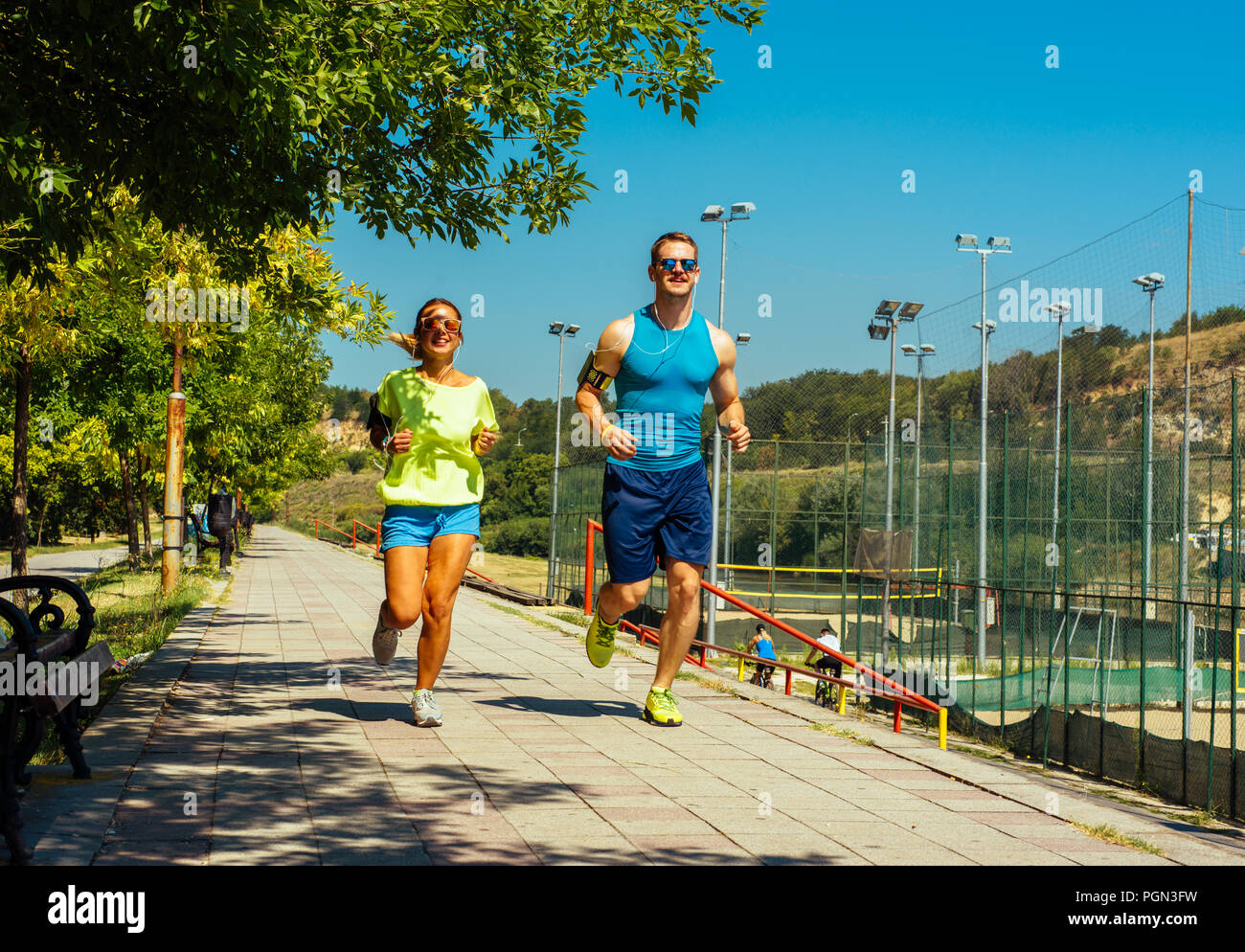 Shot of young man and woman running through the riverside track Stock ...
