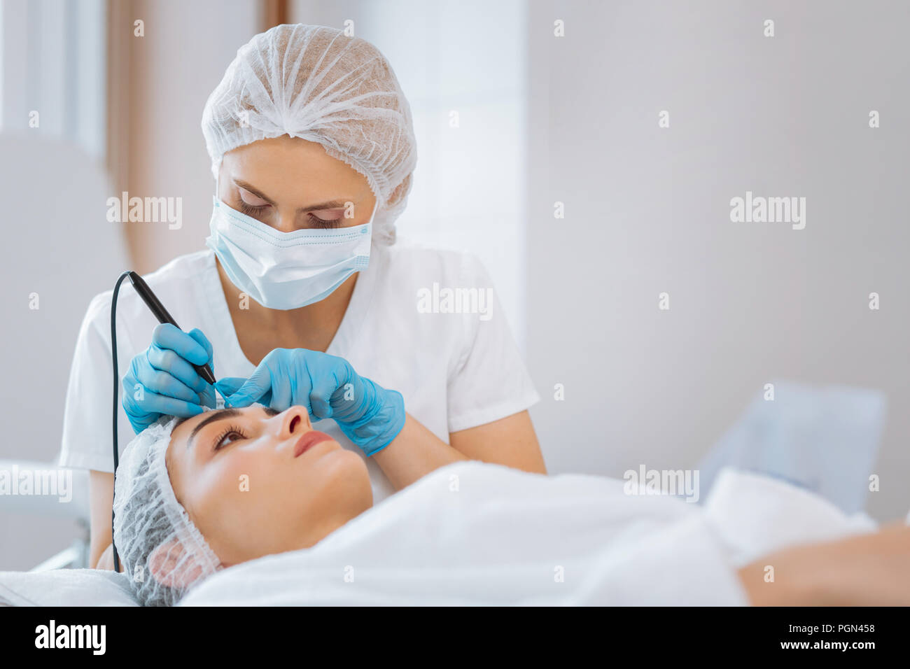 Professional serious dermatologist looking at the patients face Stock ...