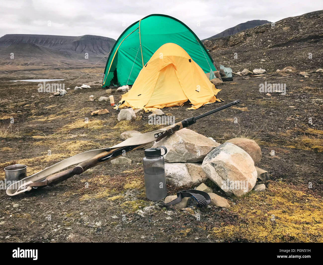 A rifle in front of tourist tents, outdoor shot, concept oif self ...