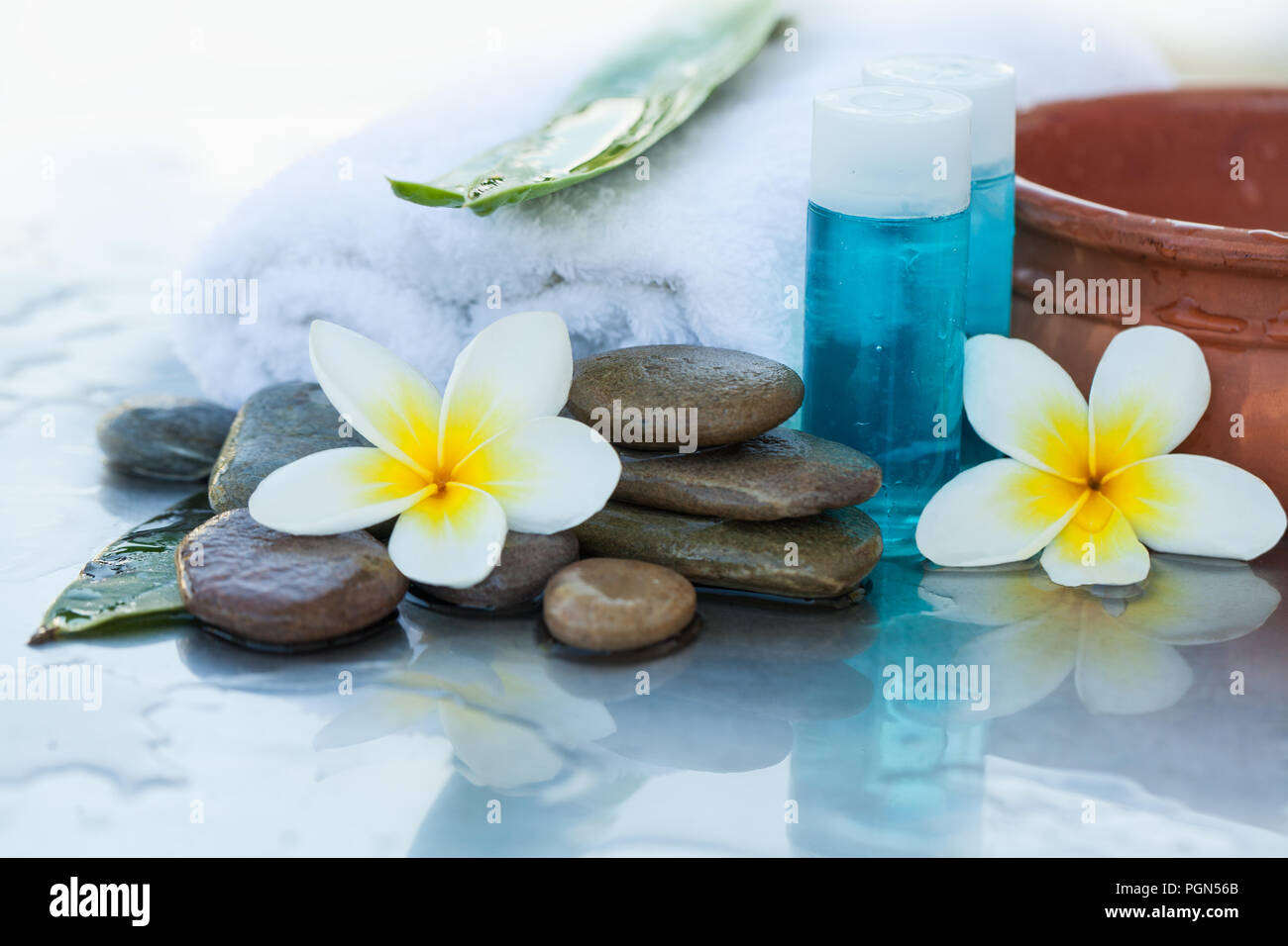 Spa Tube with oil for massage and flowers and stones Stock Photo - Alamy
