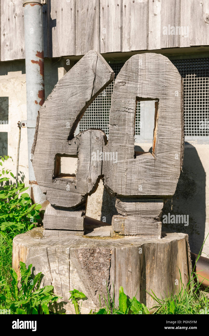 Number 60 carved from a tree stump in front of a barn in the grass ...