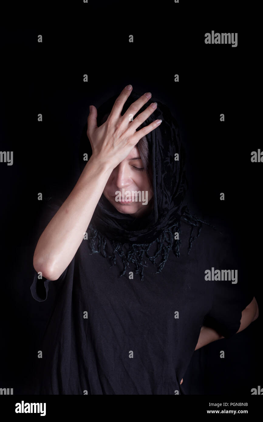 Woman on black with her hand to her head in distress gesture Stock ...