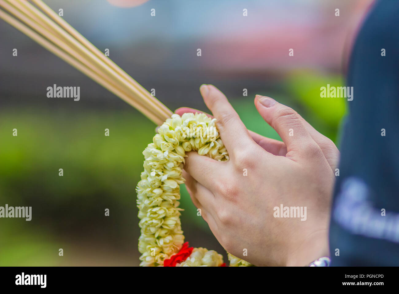 Close up people hands holding incense sticks and marigold, flower wheel ...