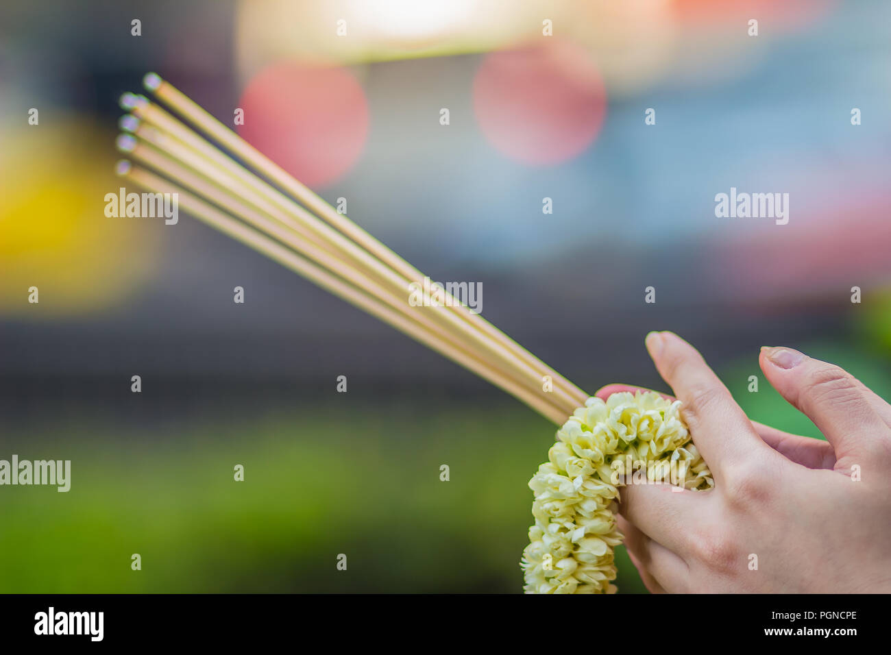 Close up people hands holding incense sticks and marigold, flower wheel ...