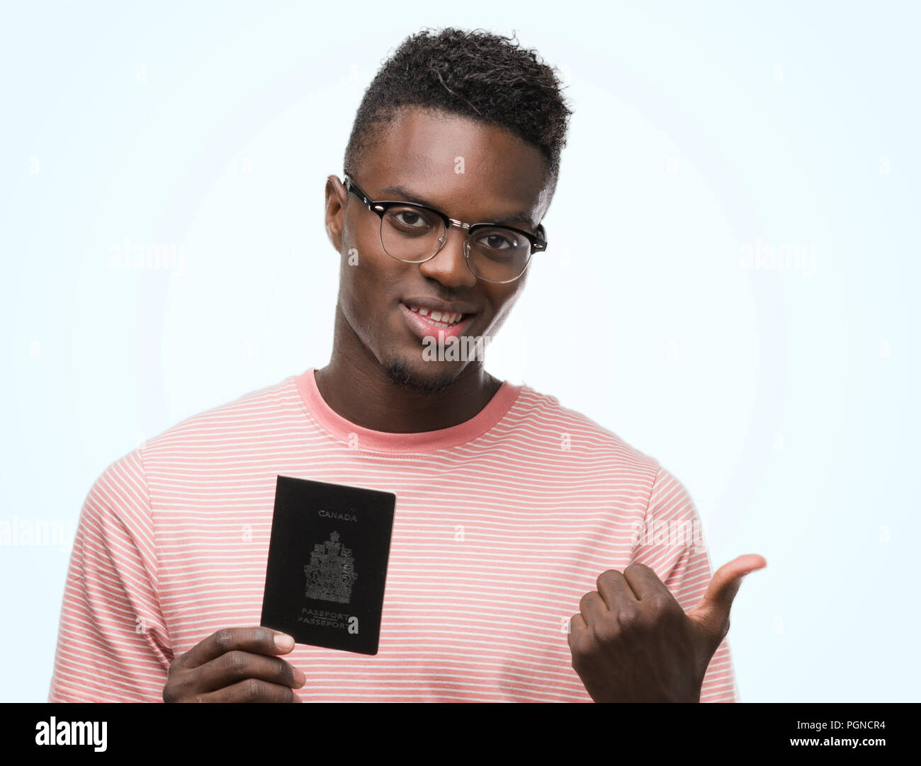 Young african american man holding canadian passport pointing with hand ...