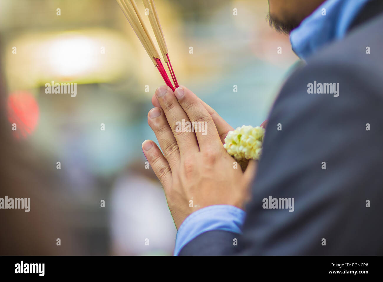 Close up people hands holding incense sticks and marigold, flower wheel ...