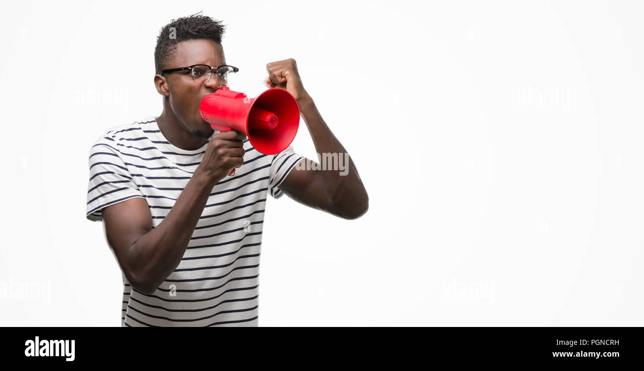 Young african american man holding megaphone annoyed and frustrated ...