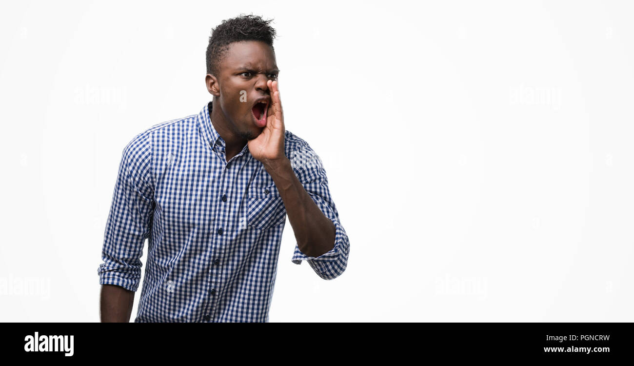 Young african american man wearing blue shirt shouting and screaming ...