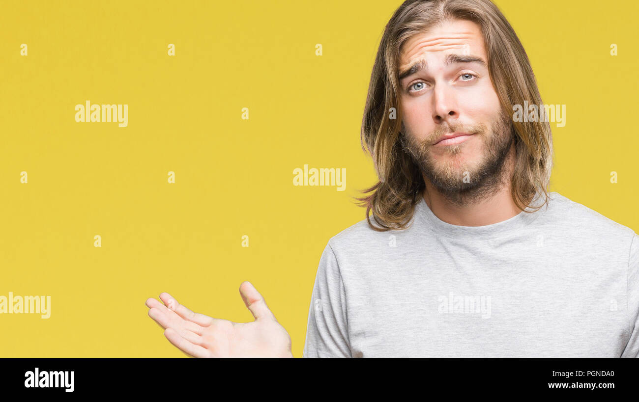 Young handsome man with long hair over isolated background clueless and ...