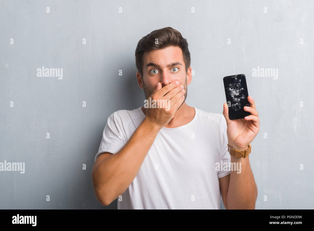 Handsome young man over grey grunge wall showing broken smartphone ...