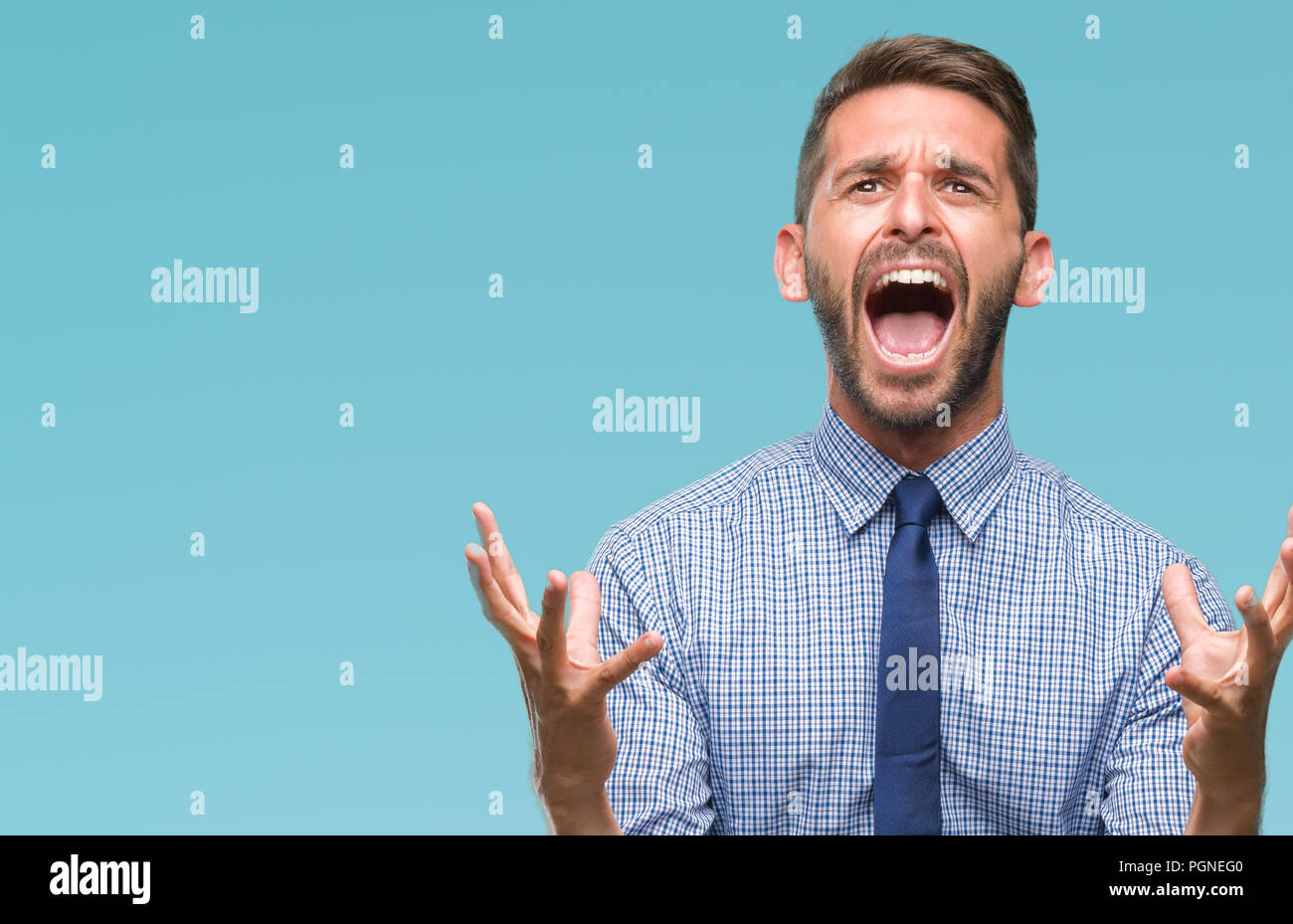 Young handsome business man over isolated background crazy and mad ...