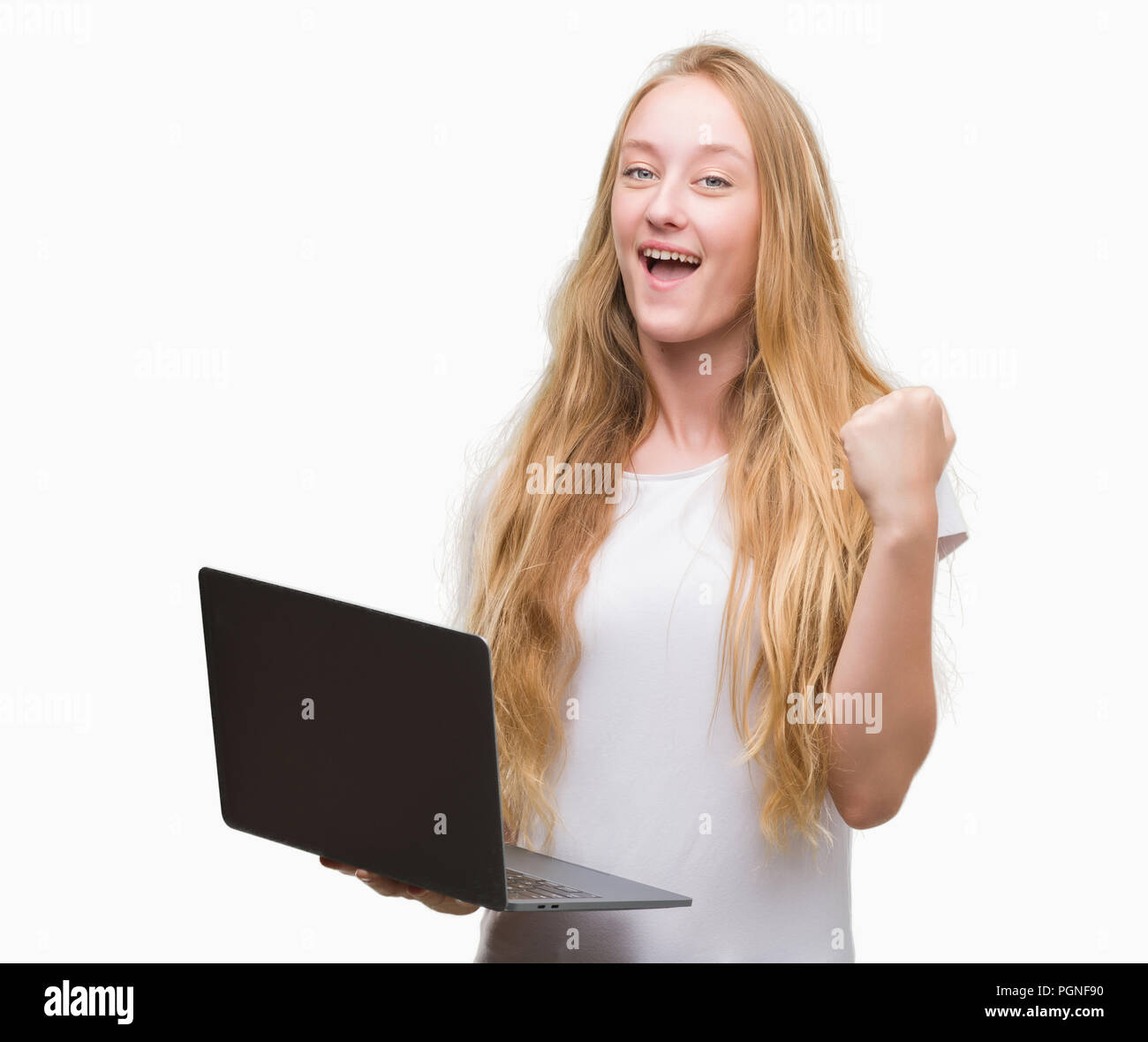 Blonde teenager woman using computer laptop screaming proud and ...
