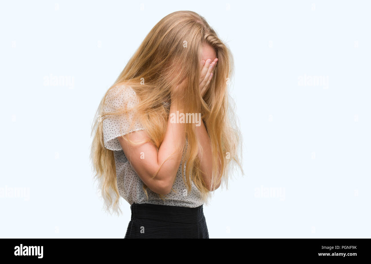 Blonde teenager woman wearing moles shirt with sad expression covering ...