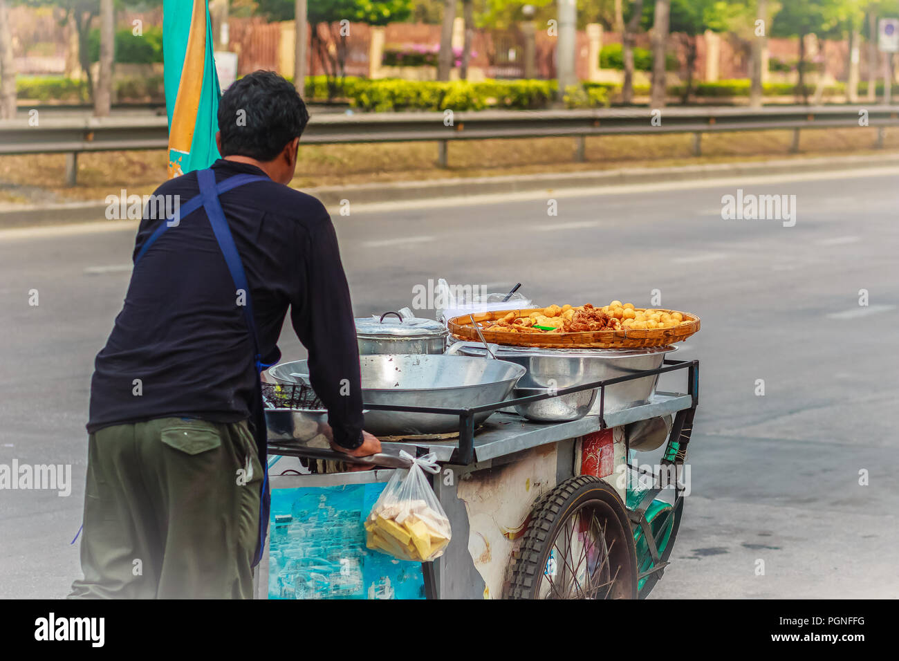 Unidentified street hawker pushing a mobile kitchen cart on a street ...