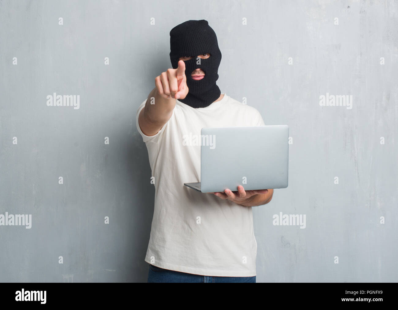 Young caucasian hacker man over grey grunge wall doing cyber attack ...