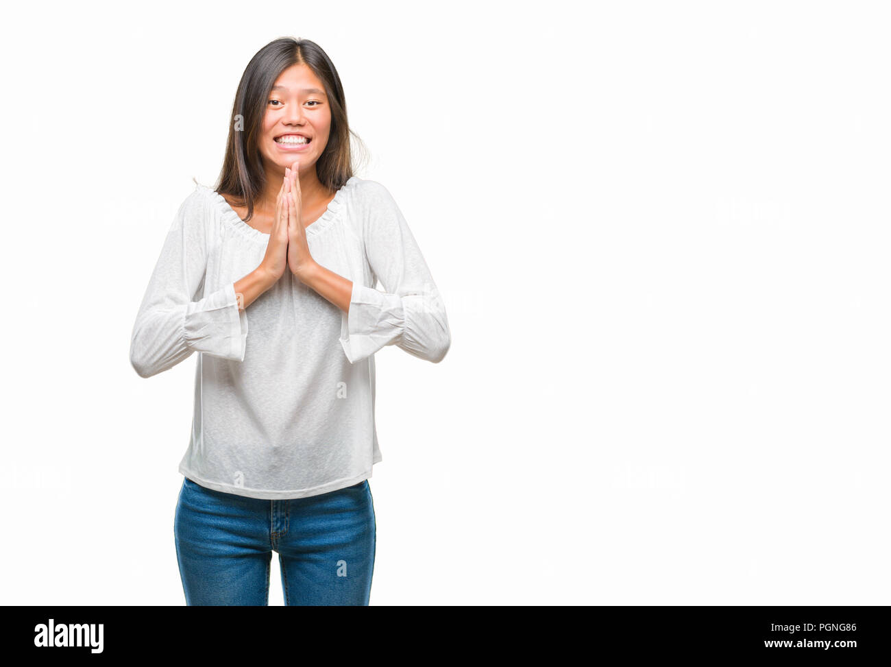 Young asian woman over isolated background praying with hands together ...