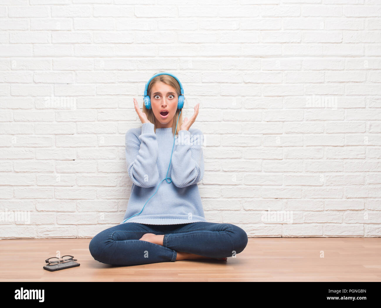 Beautiful young woman sitting on the floor listening music wearing ...