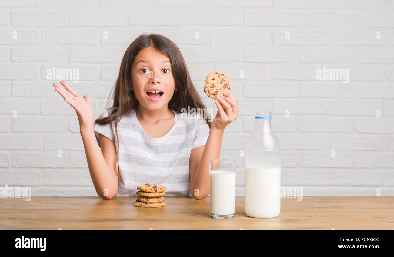 Young hispanic kid sitting on the table drinking milk and eating ...