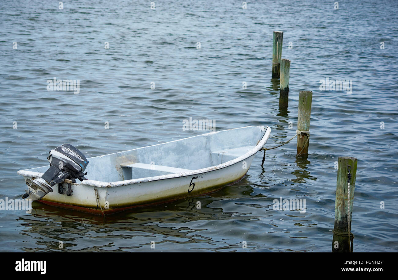 small boat with engine tied to post in water Stock Photo - Alamy