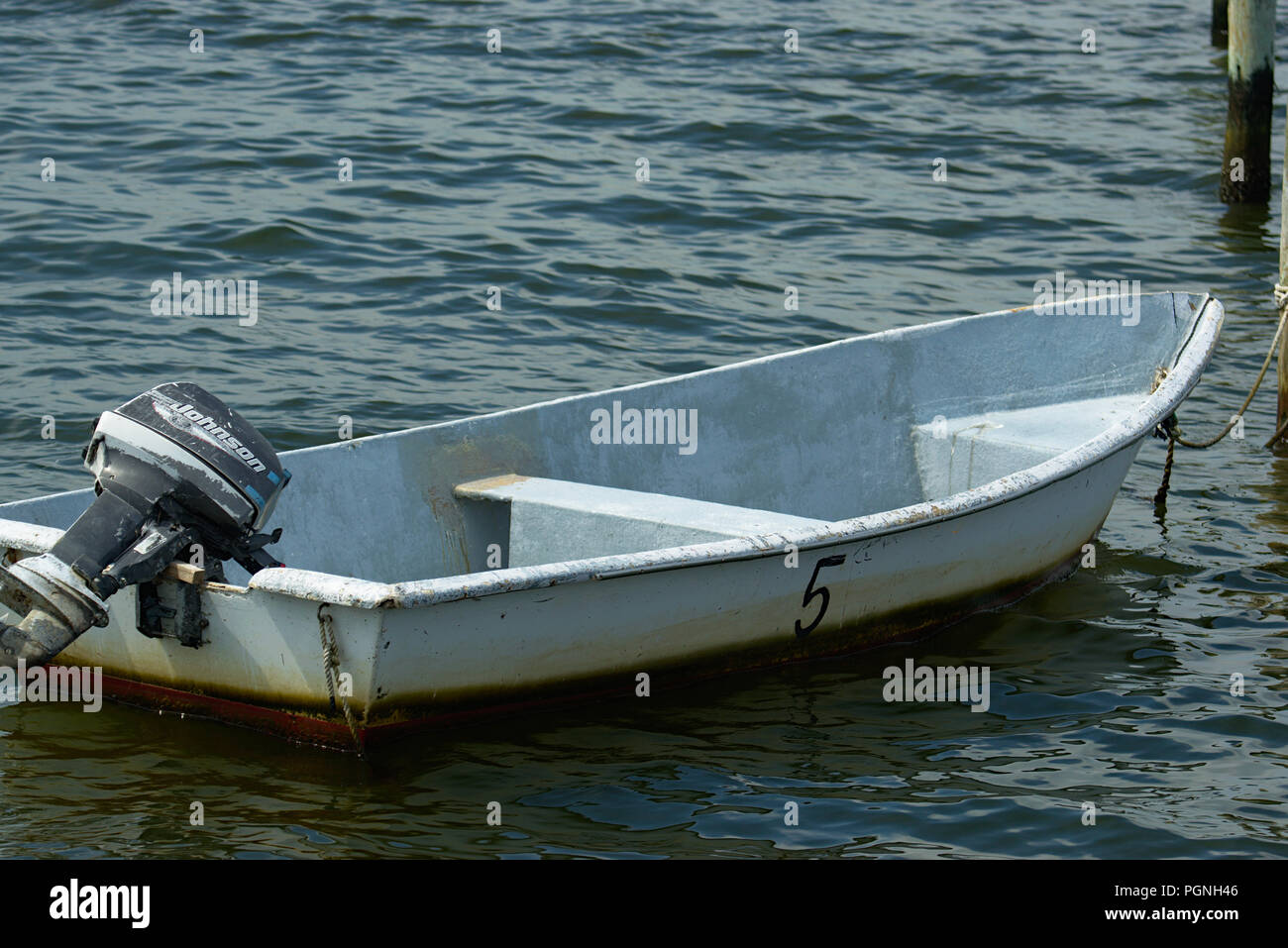 small boat with engine tied to post in water Stock Photo - Alamy