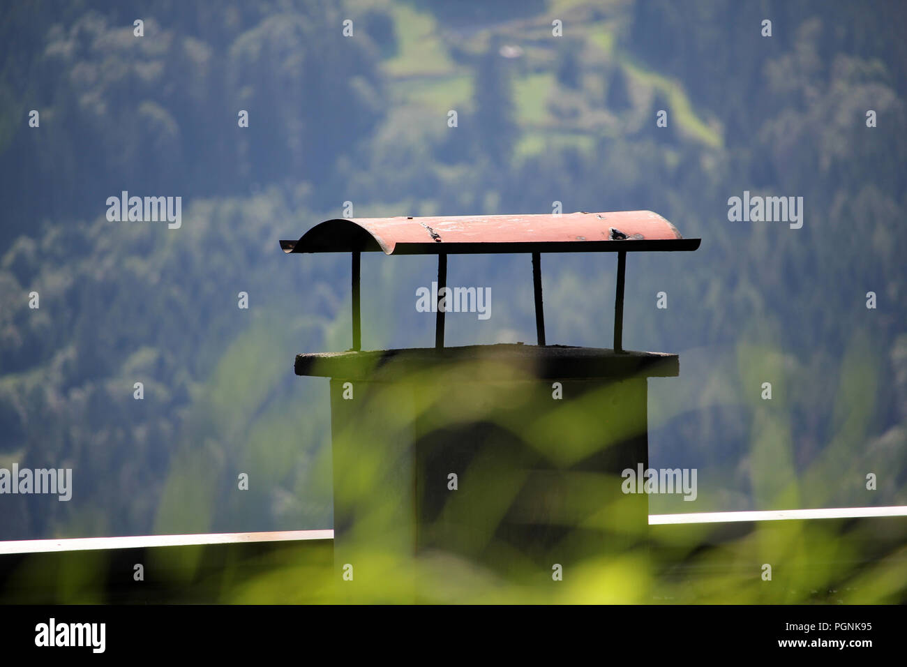 Old chimney with metal cover against a mountain with green forest Stock ...