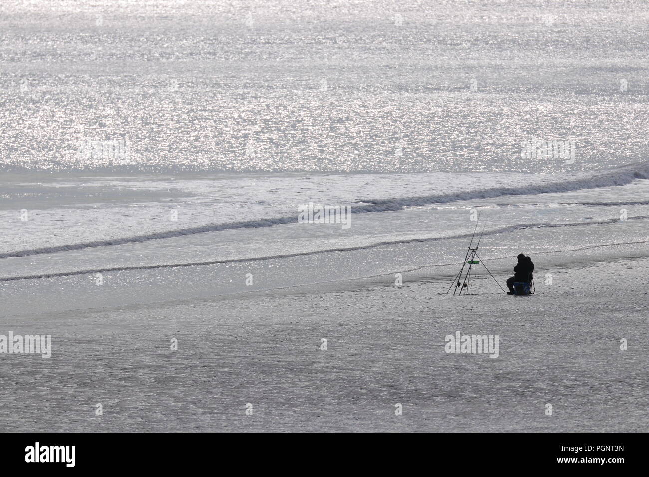 A silhouette of a fisherman on the beach at Reighton Gap in North ...