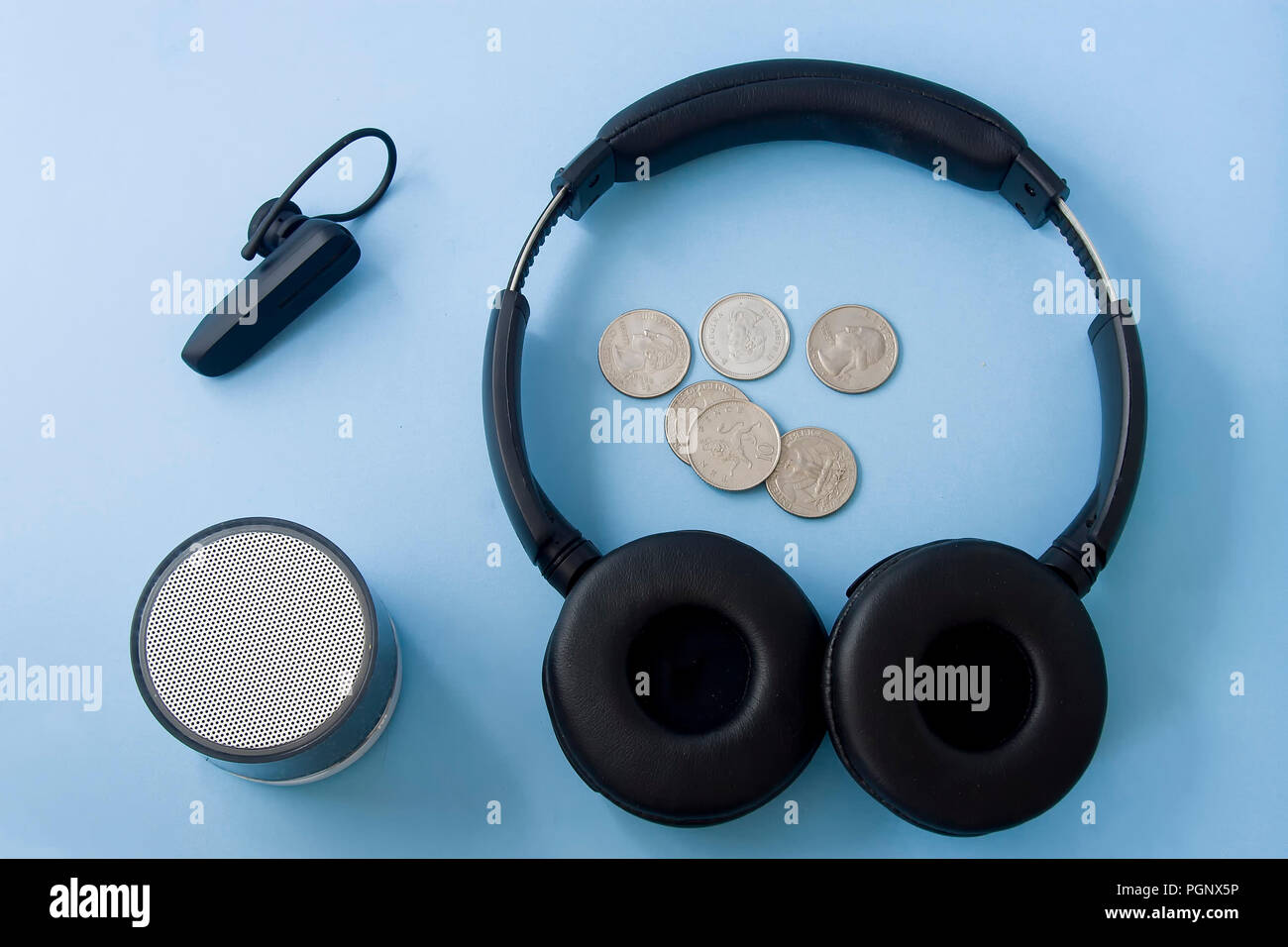 Coins, wireless headset, headphones and speaker on blue pastel isolated ...