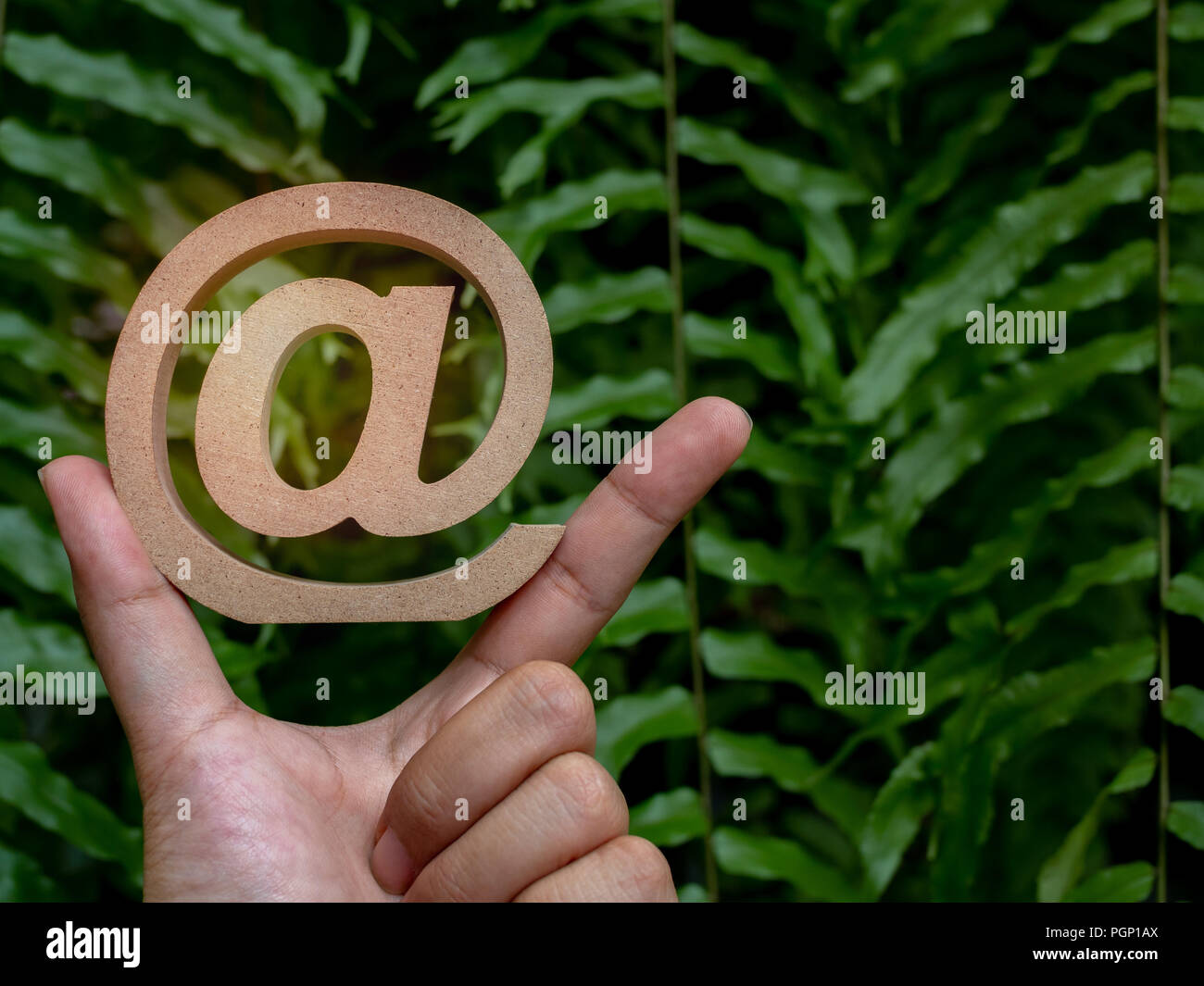 Wooden E-mail address symbol on correct pointing hand sign, arroba icon ...