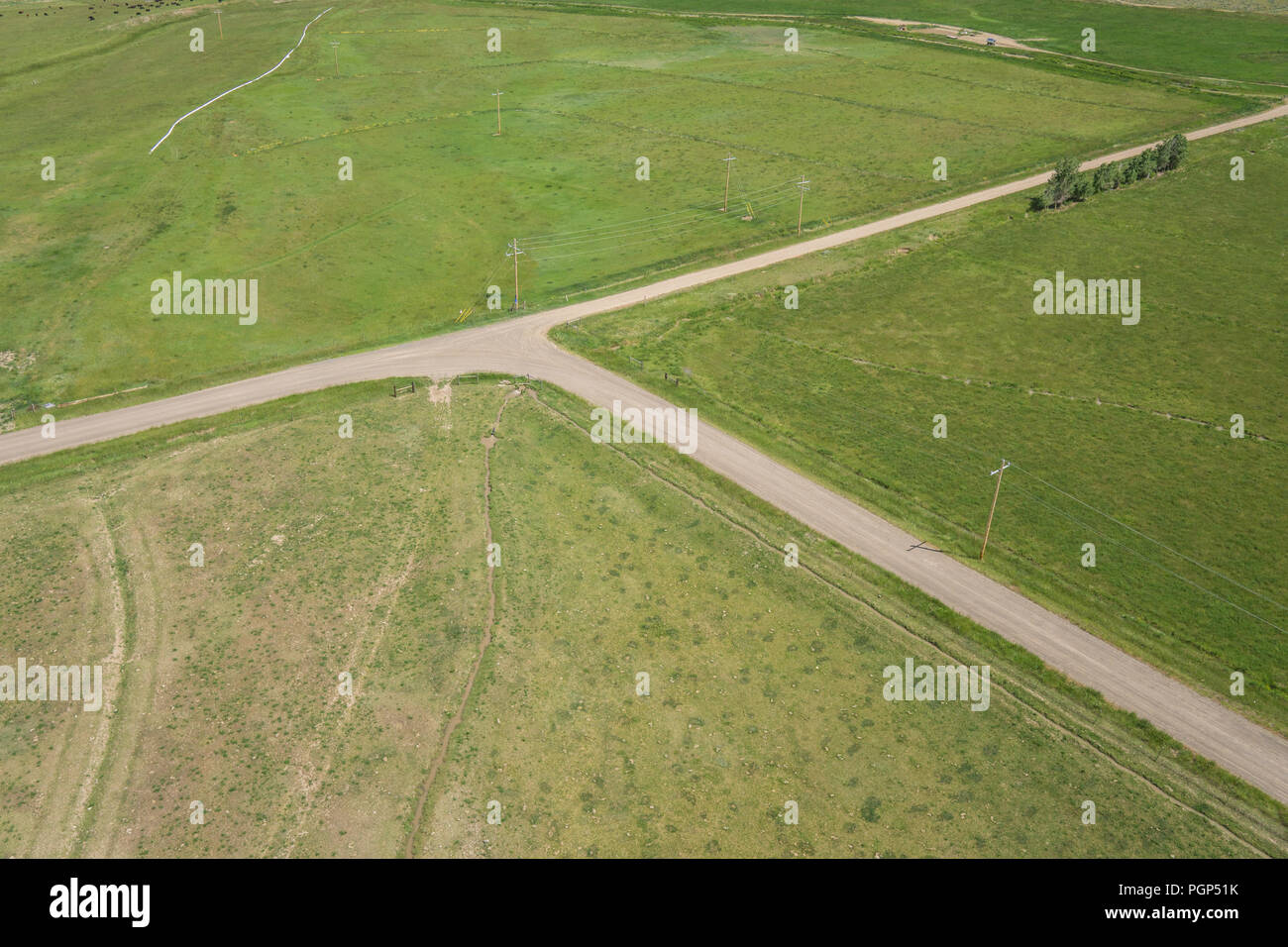 Intersection of dirt and gravel farming roads between green fields in ...