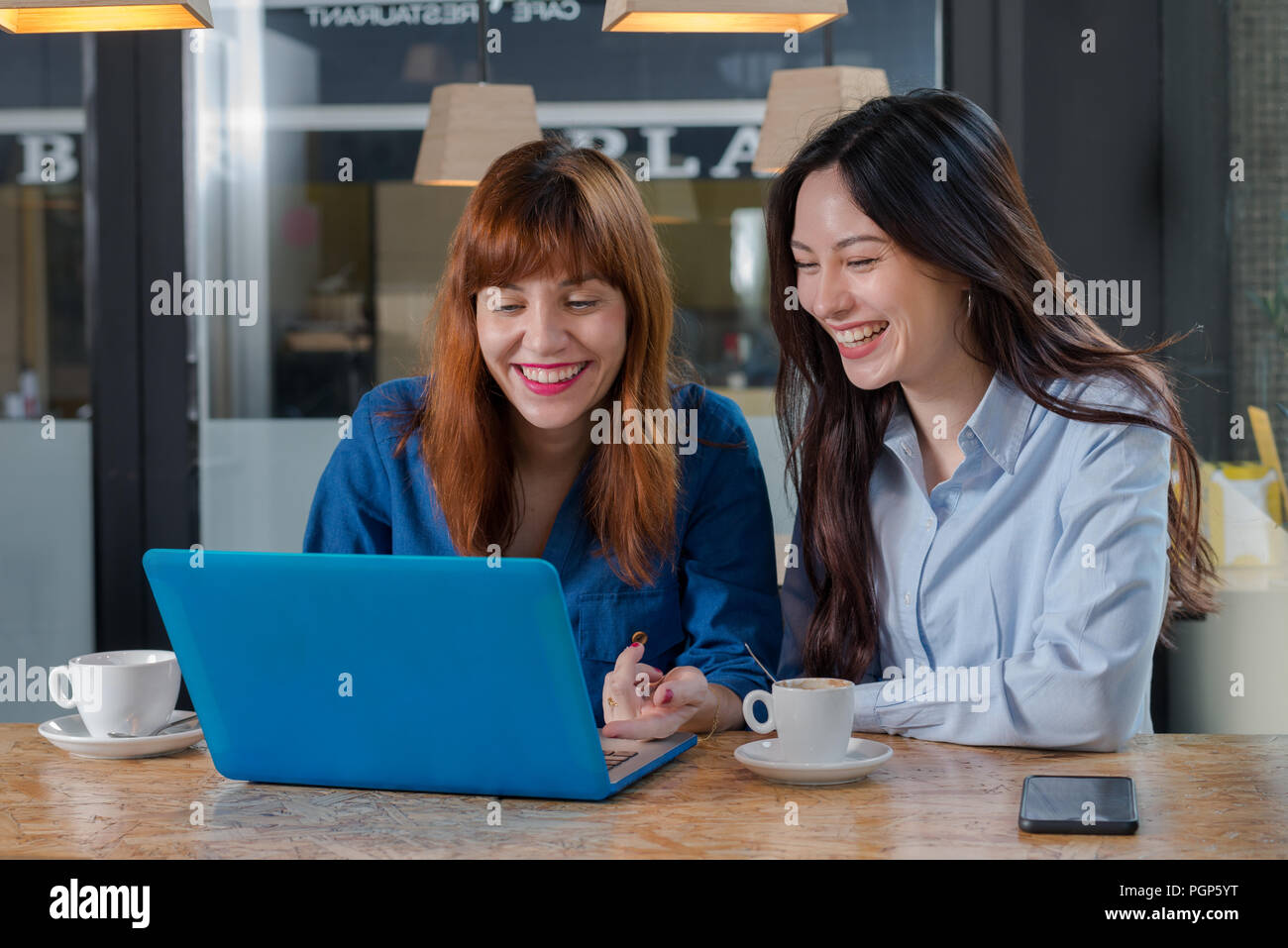 Two friends with laptop laugh Stock Photo - Alamy