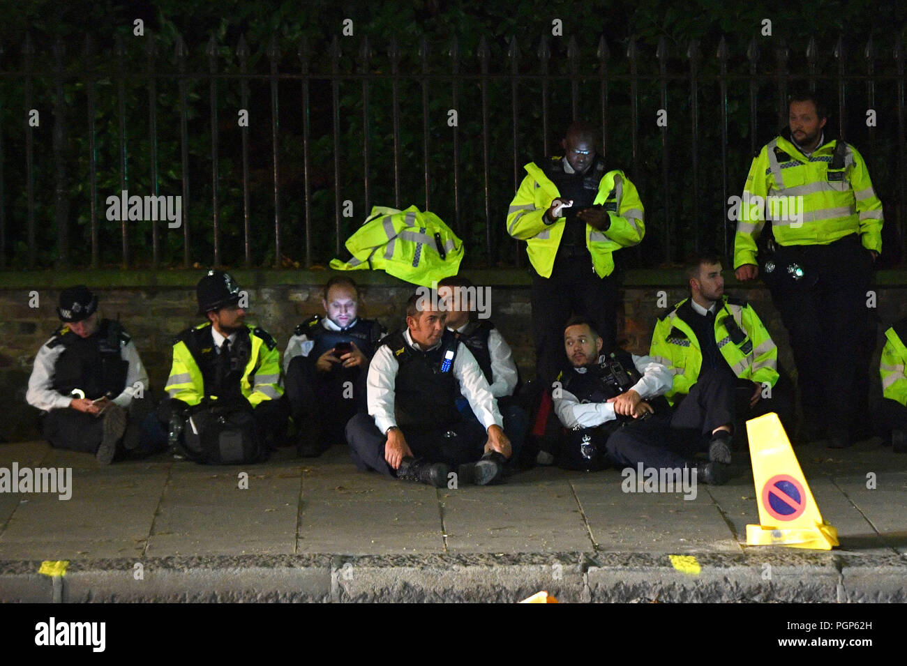 Police officers sit down on the pavement, as the Notting Hill Carnival ...
