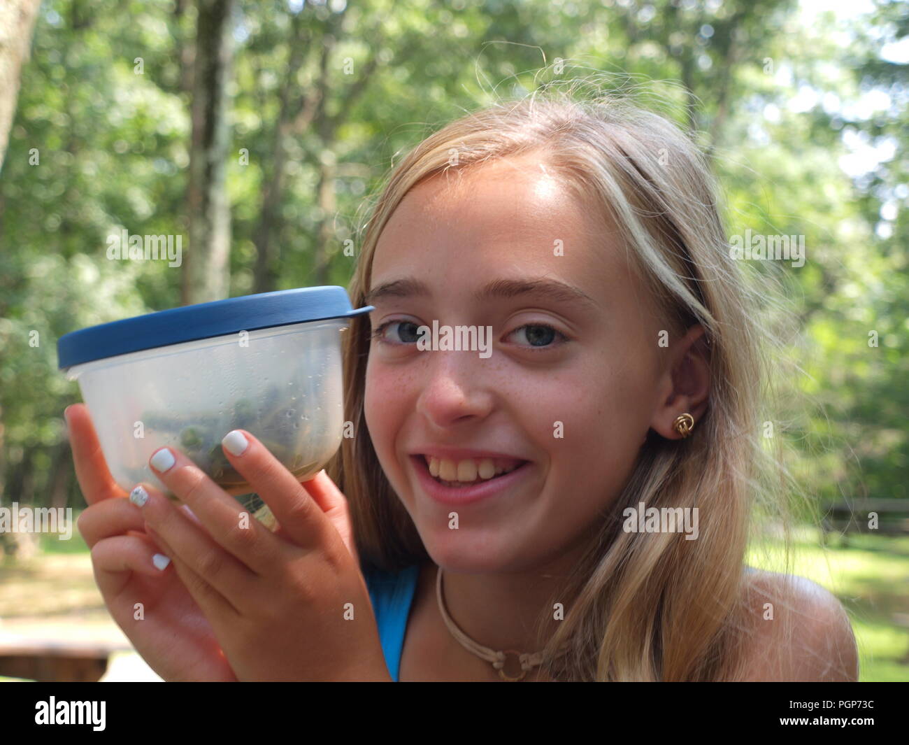 cute blonde girl holding a plastic container of string beans at a ...