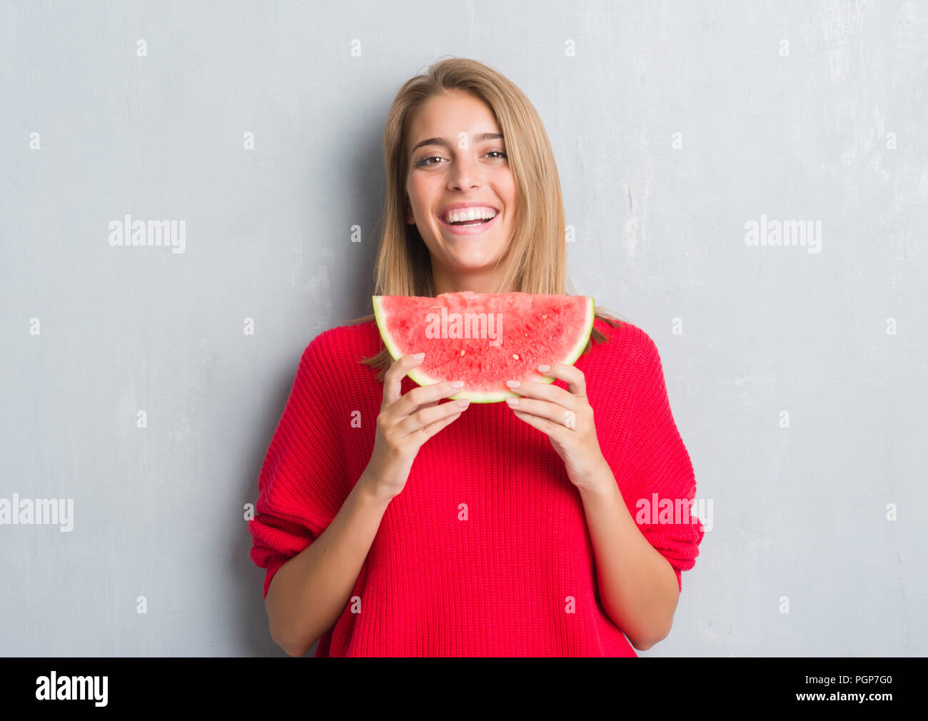 Beautiful young woman over grunge grey wall eating water melon with a ...