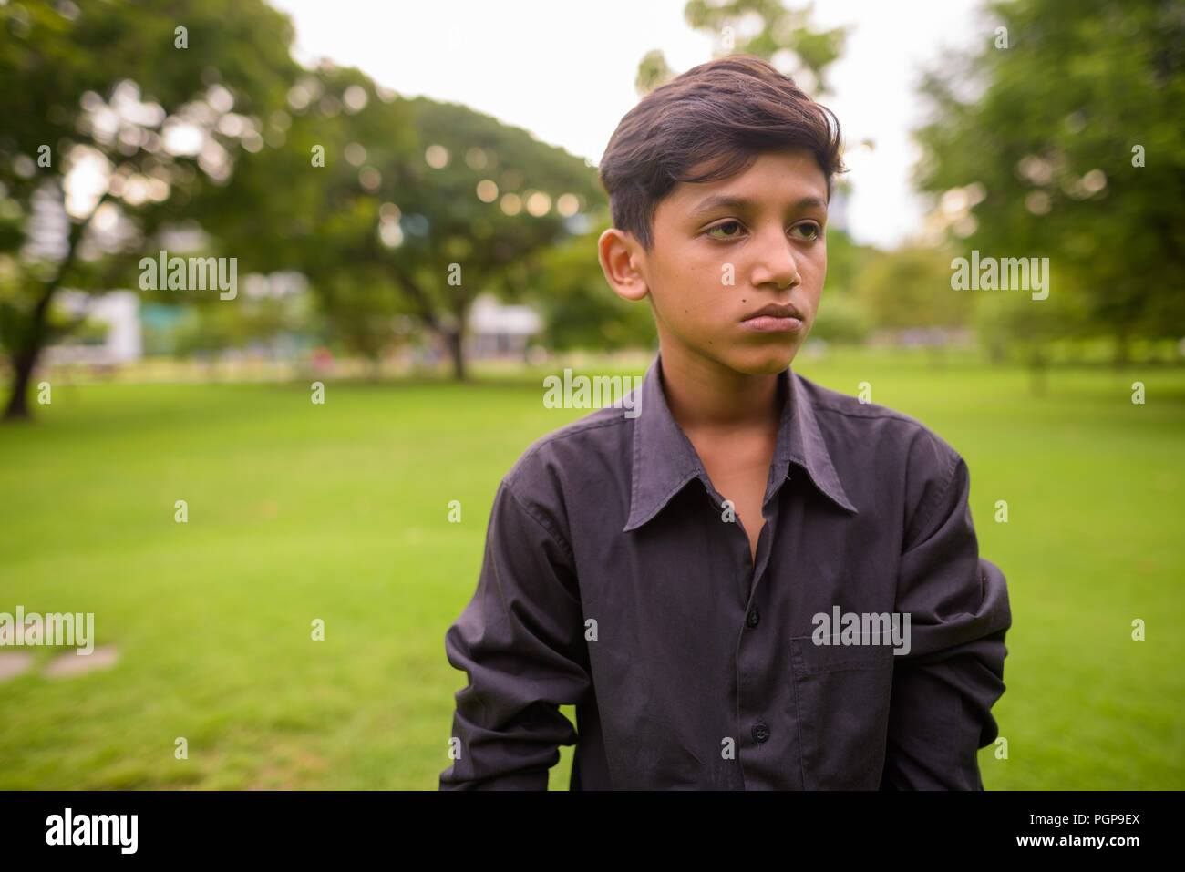 Portrait of young Indian boy relaxing at the park Stock Photo - Alamy