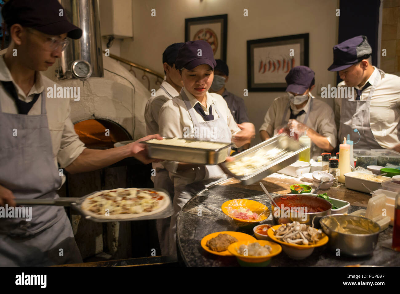 Staff are busy preparing pizzas at Pizza 4Ps flagship store in Ho Chi ...