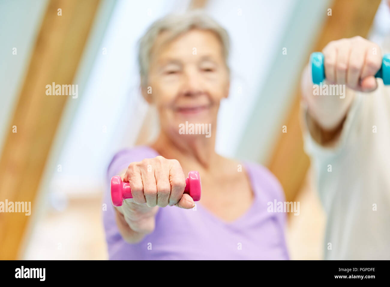 Senior woman doing dumbbell training in fitness course for health and ...