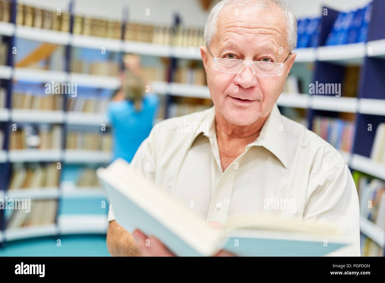 Senior in the library in the retirement home with a book expanding his ...