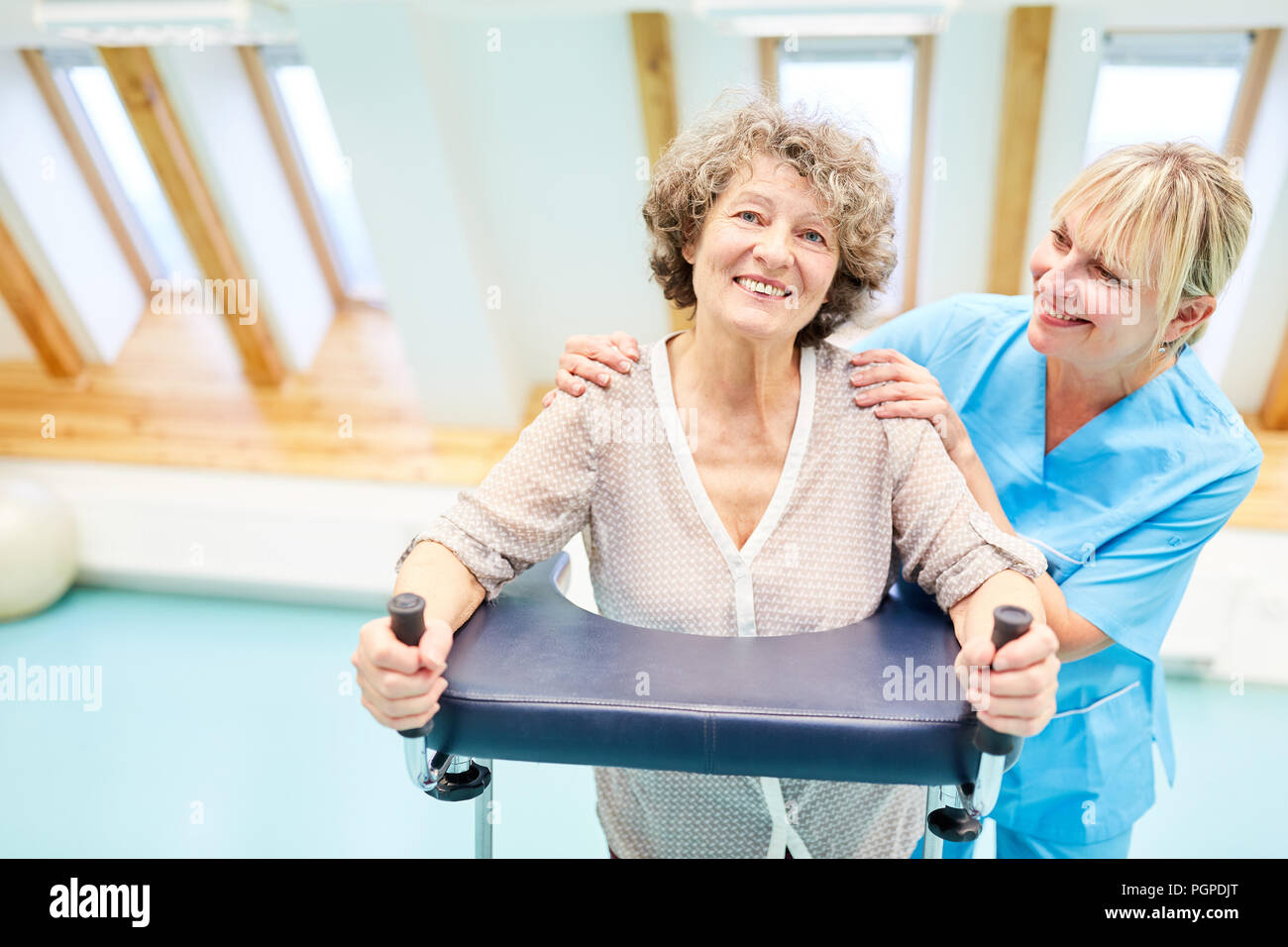 Happy senior woman with walker and rehab therapist in physiotherapy ...