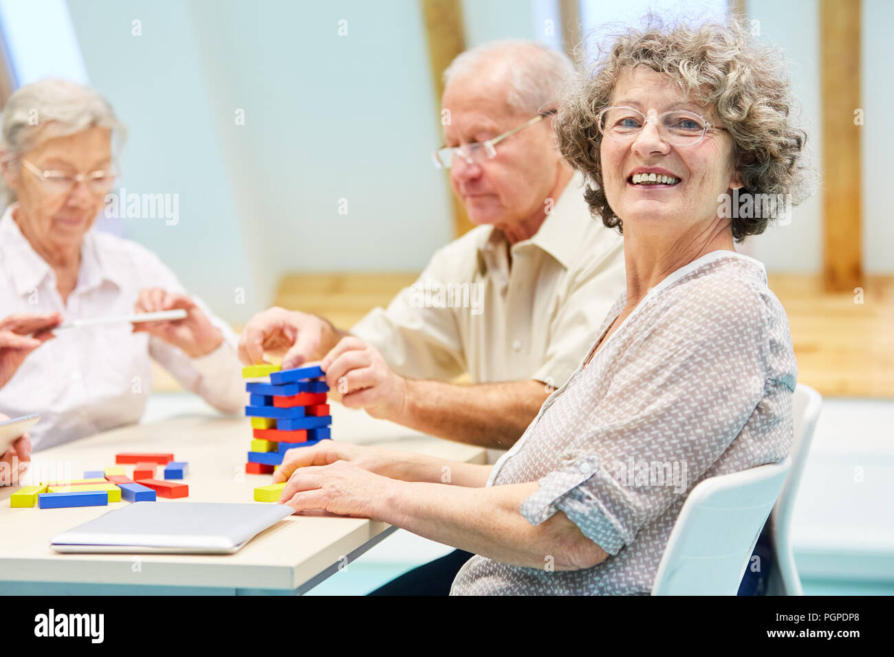 Smiling seniors with dementia build a tower of building blocks in ...
