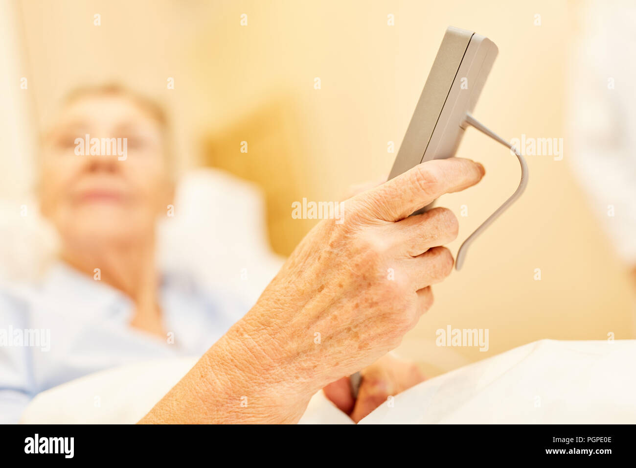 The patient is lying in bed holding the remote control from the nursing ...