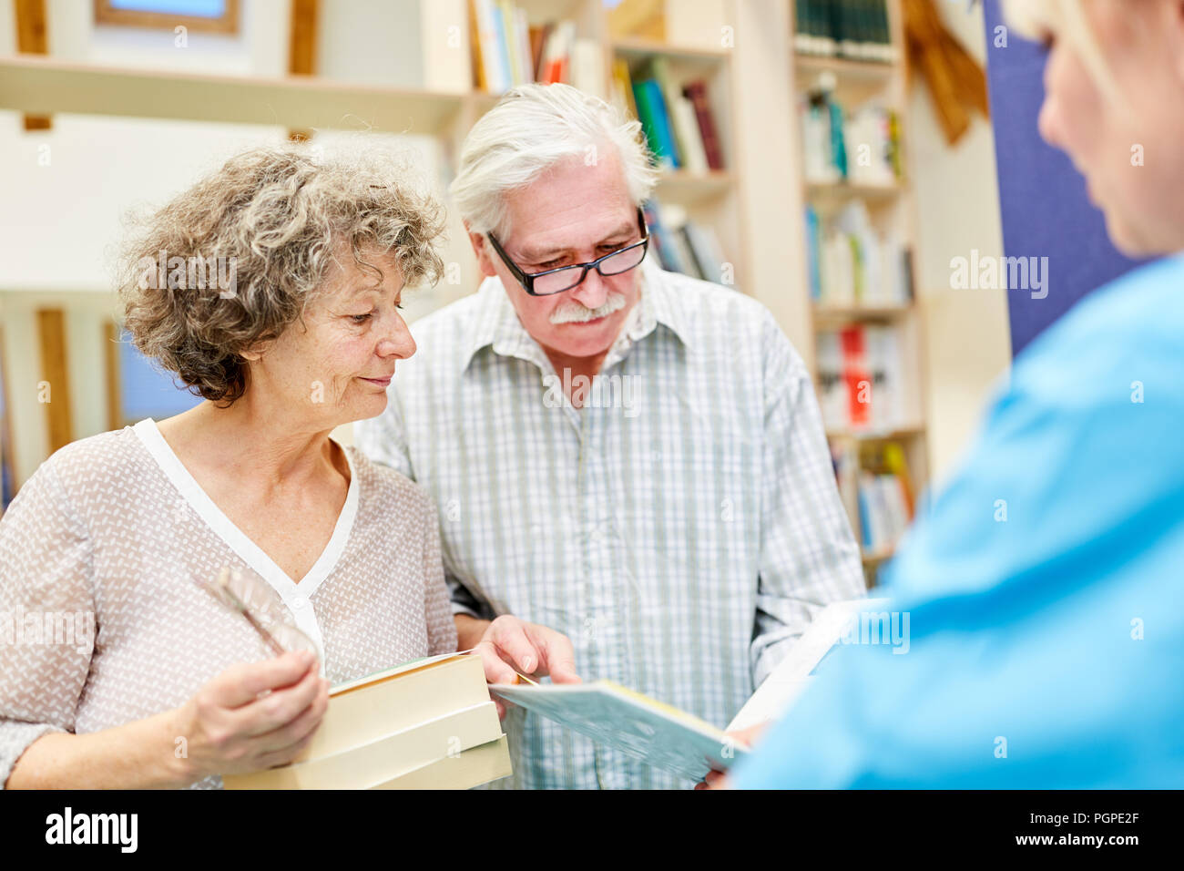 Senior couple reading a book about continuing education in the library ...