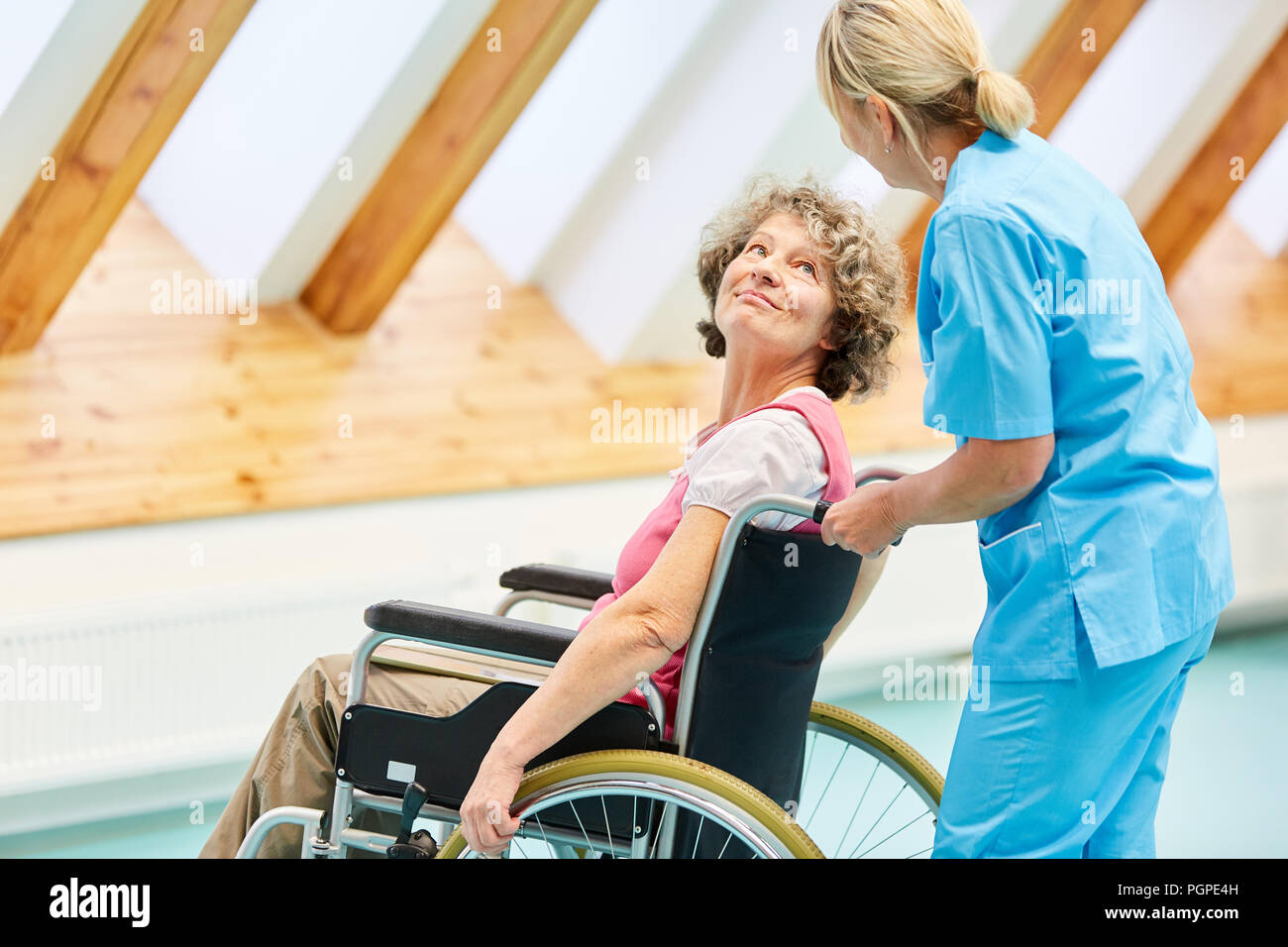 Senior woman as a patient in a wheelchair is being cared for by a ...