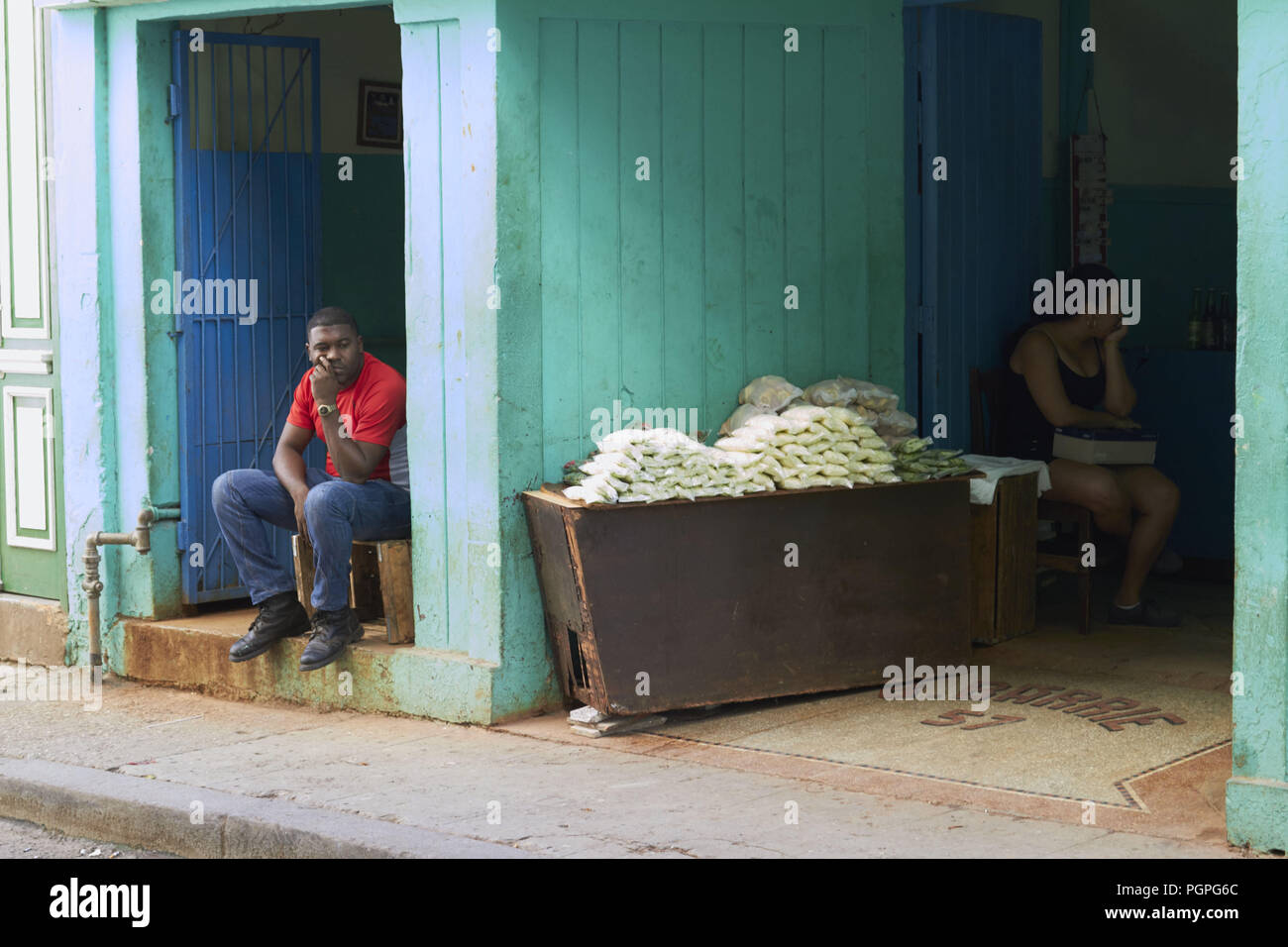Havana, Cuba. 27th Dec, 2016. A man relaxes in one doorway, as a woman ...