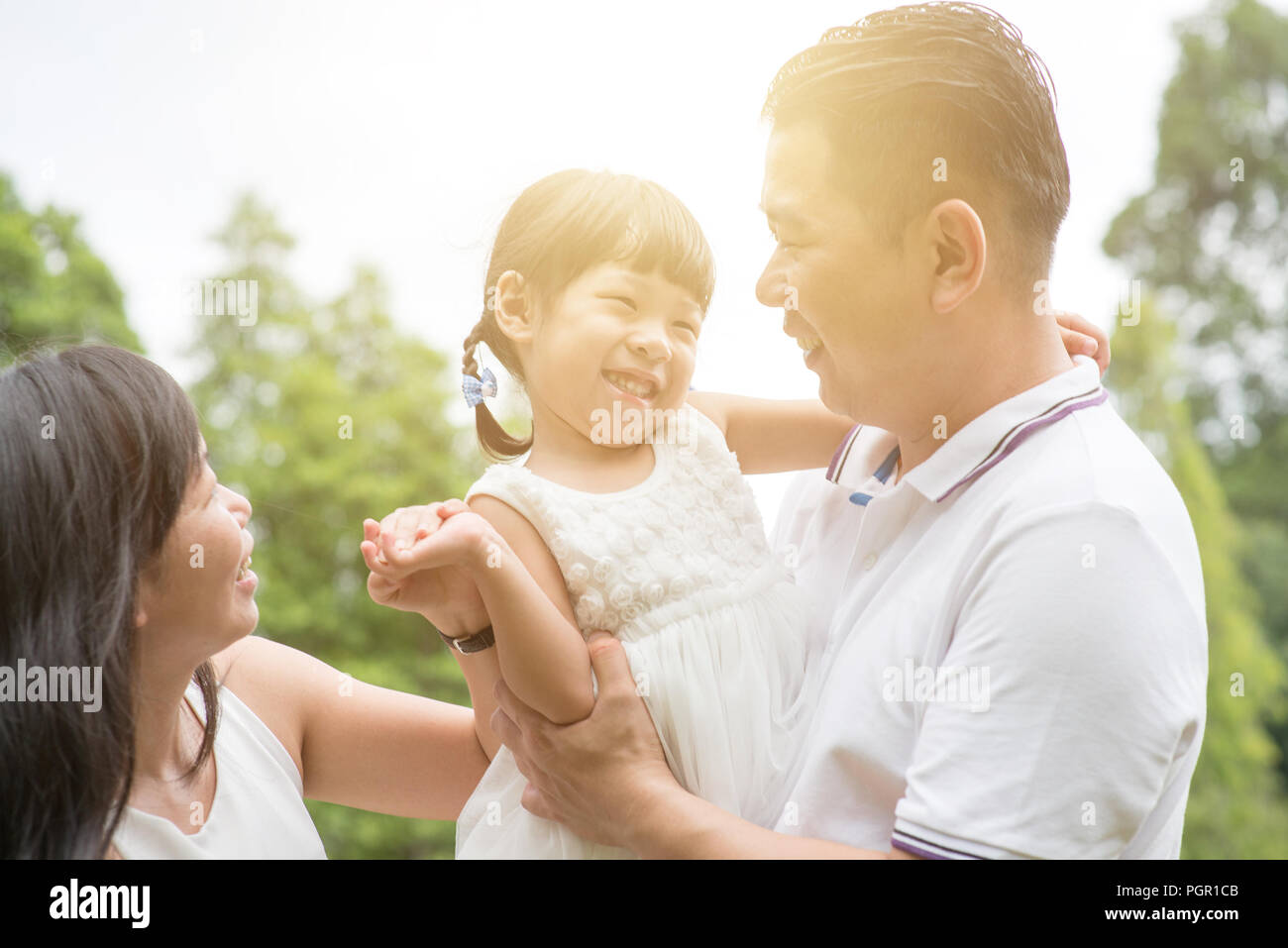 Happy parents and child bonding at green park. Asian family outdoors ...
