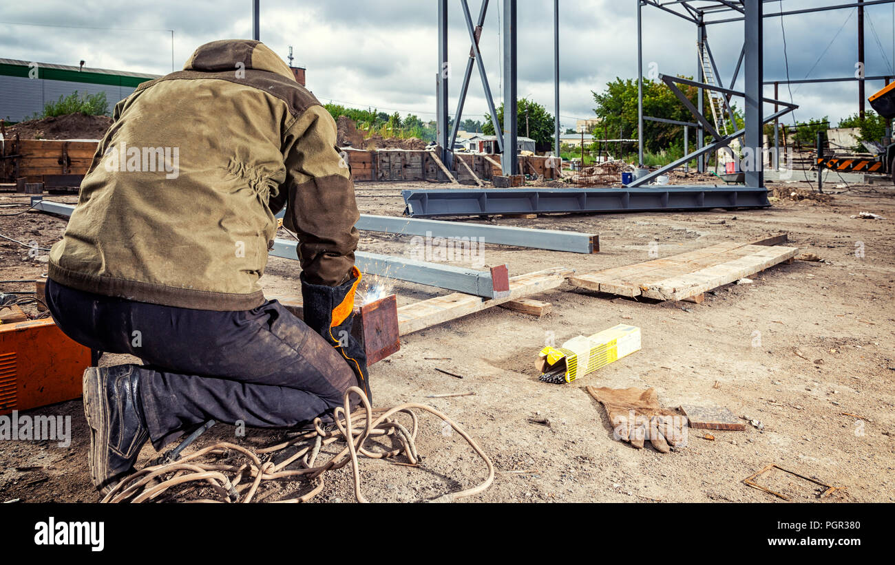 Man welder in welding mask, building uniform and blue protective gloves ...