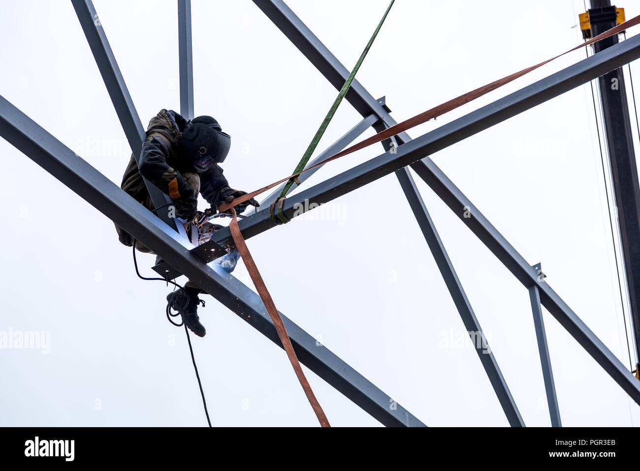 A man welder working at height with insurance in welding mask is weld ...