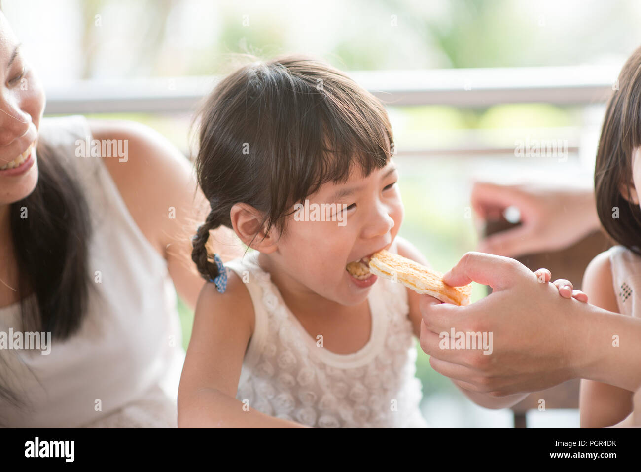 Daddy feed bread to child at cafe. Asian family outdoor lifestyle with ...