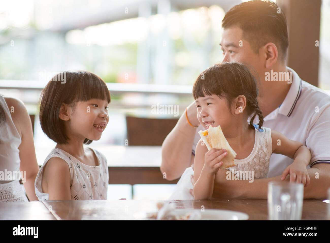 Happy children eating toast bread at cafeteria. Asian family outdoor ...