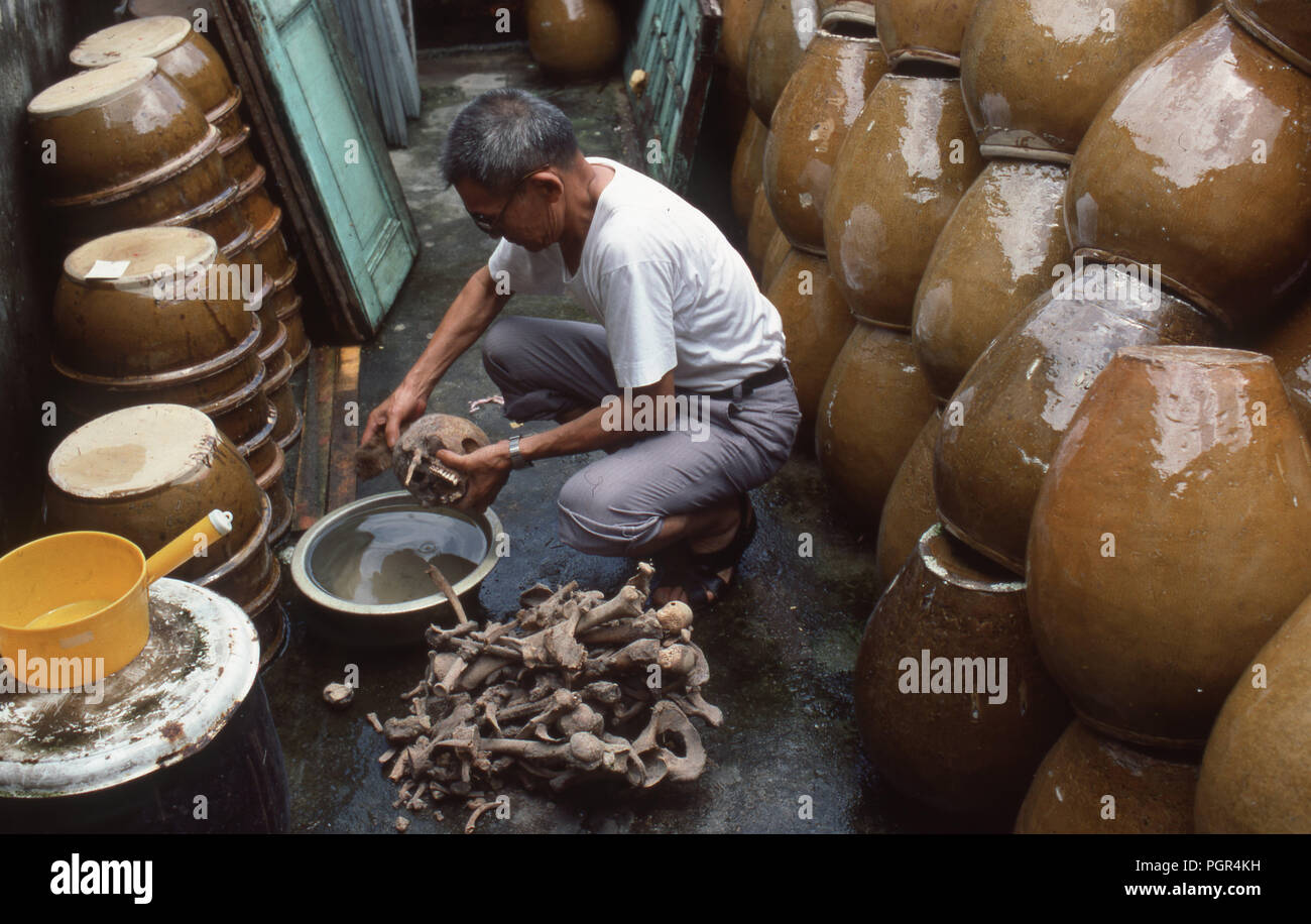 A Man removes bones from a earthenware earthenware jar and washes them ...